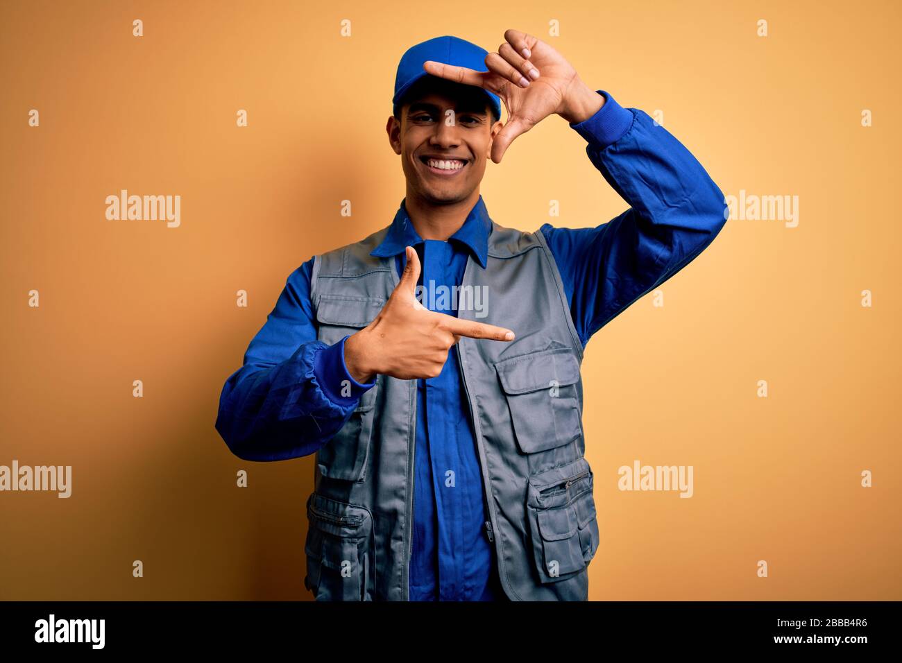 Young handsome african american handyman wearing worker uniform and cap ...