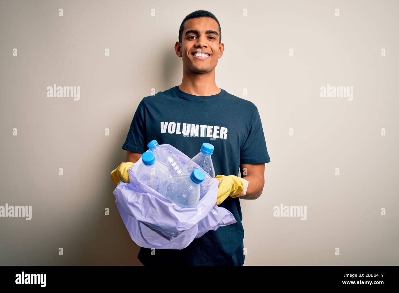Handsome african american volunteer man recycling plastic bottles ...