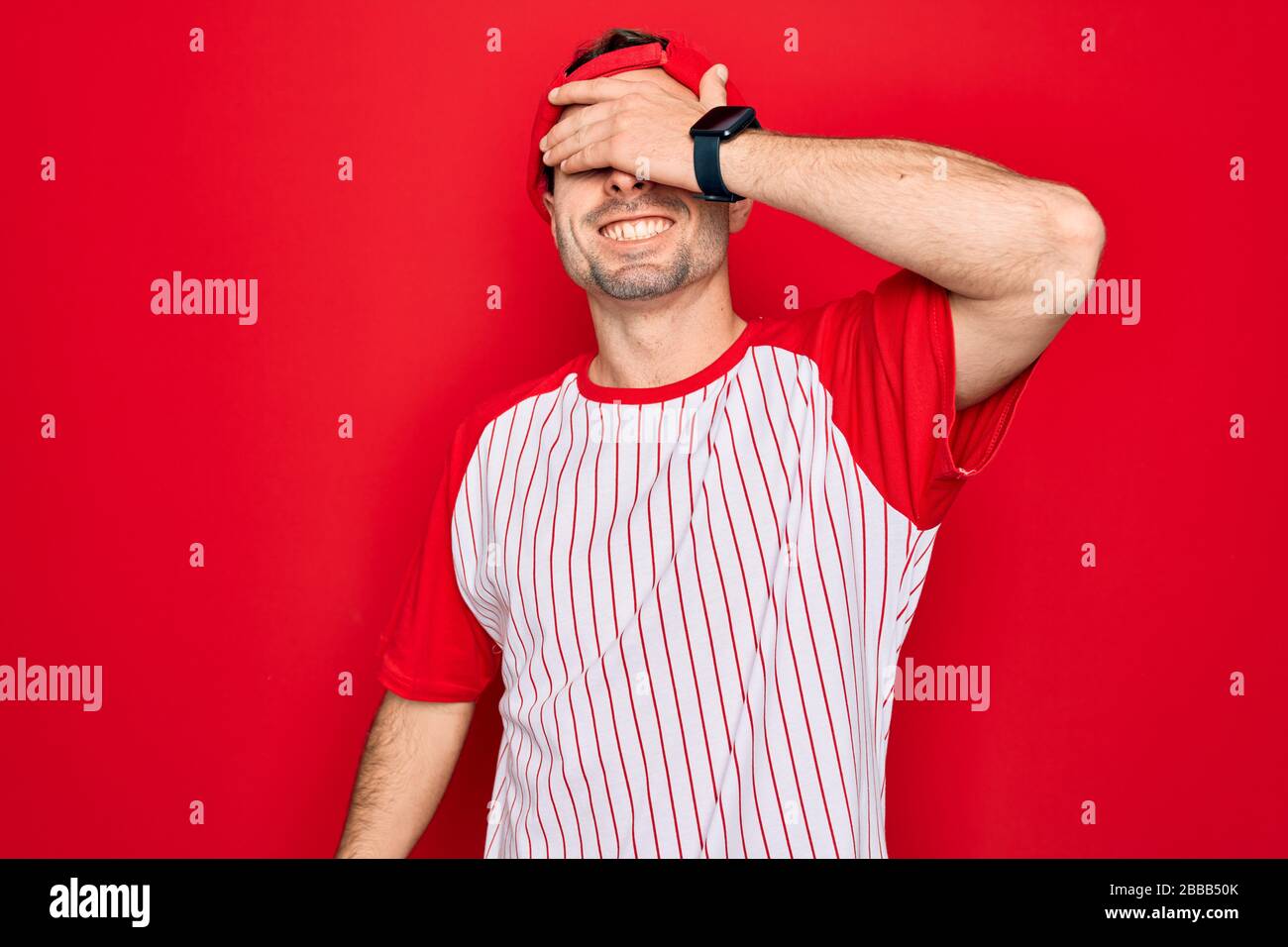 Young handsome sporty man with blue eyes wearing striped baseball t ...