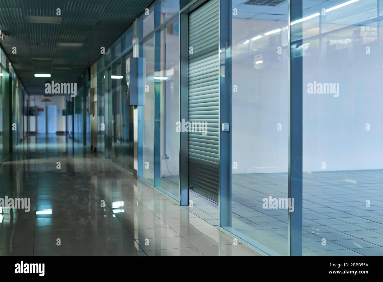 blurred dim dark deserted mall corridor with empty retail space without ...
