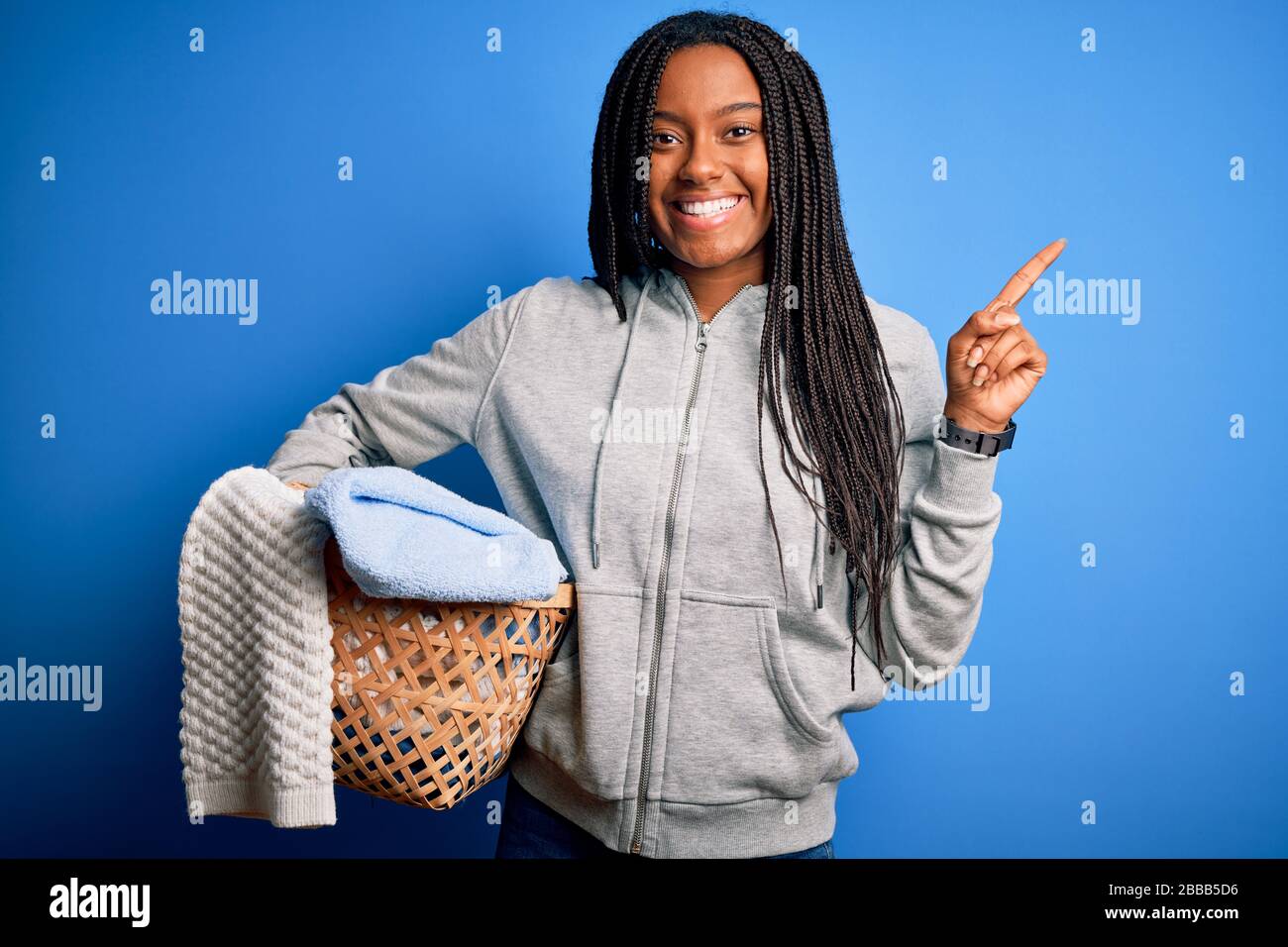 Young african american girl doing domestic housework holding laundry ...