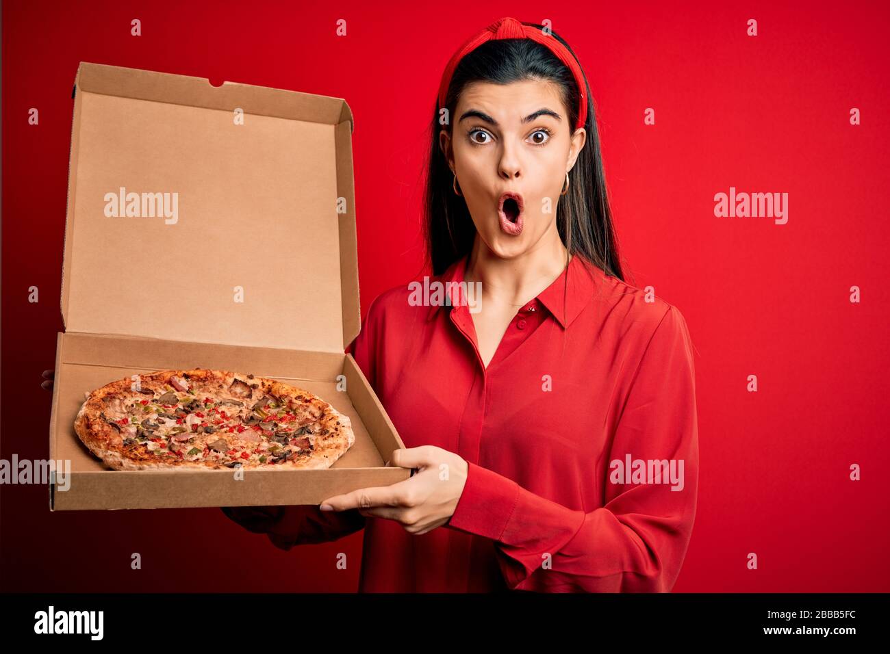 Young beautiful brunette woman holding delivery box with Italian pizza ...