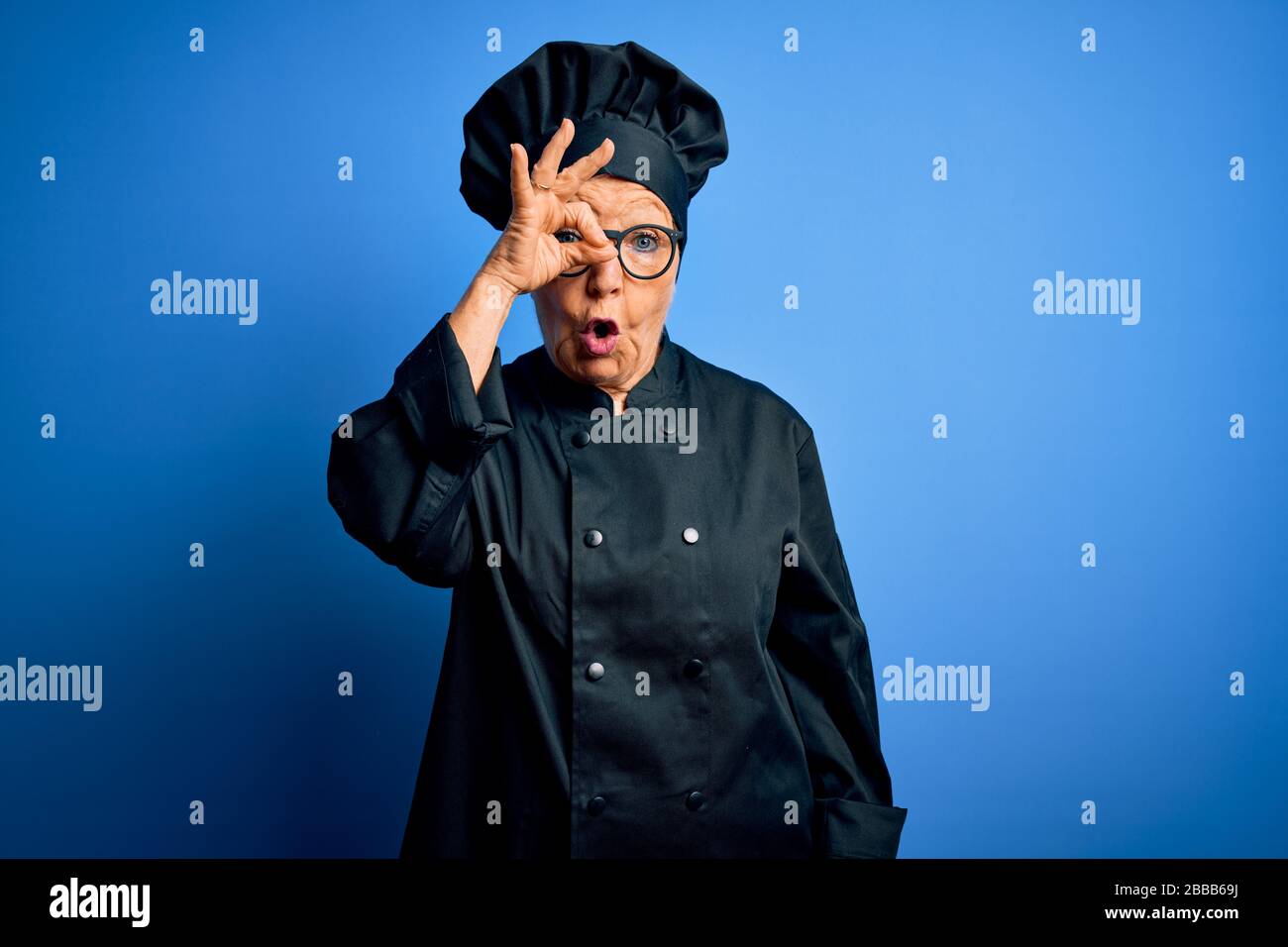 Senior beautiful grey-haired chef woman wearing cooker uniform and hat ...