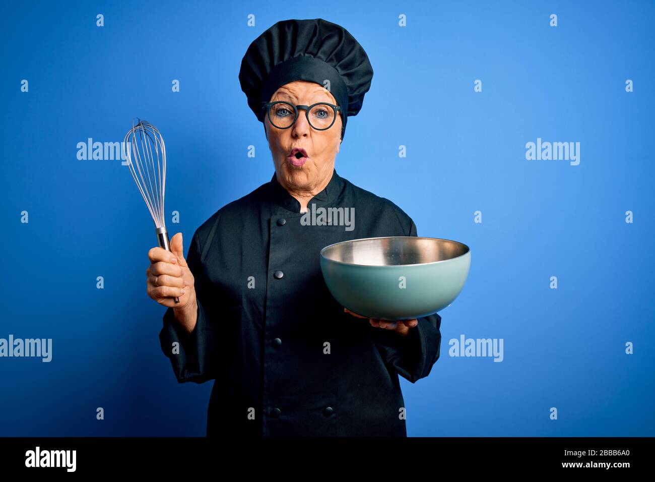Senior beautiful grey-haired chef woman wearing cooker uniform and hat ...