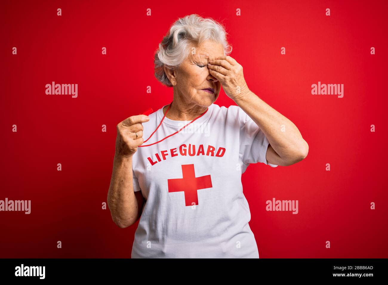 Senior beautiful grey-haired lifeguard woman wearing t-shirt with red ...