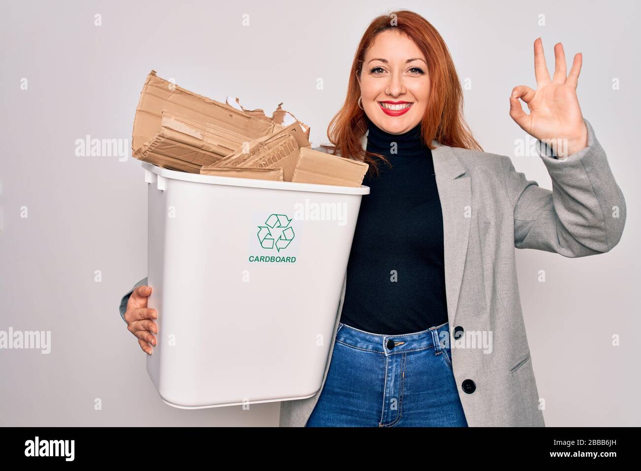 Young beautiful redhead woman recycling holding trash can with ...
