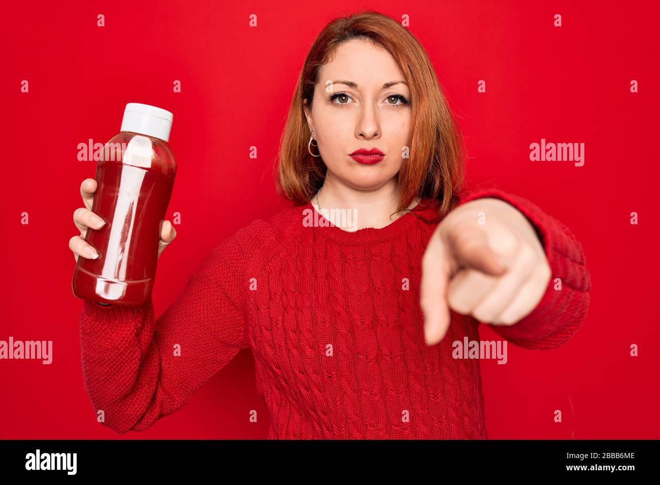 Beautiful redhead woman holding bottle of ketchup sauce condiment over ...