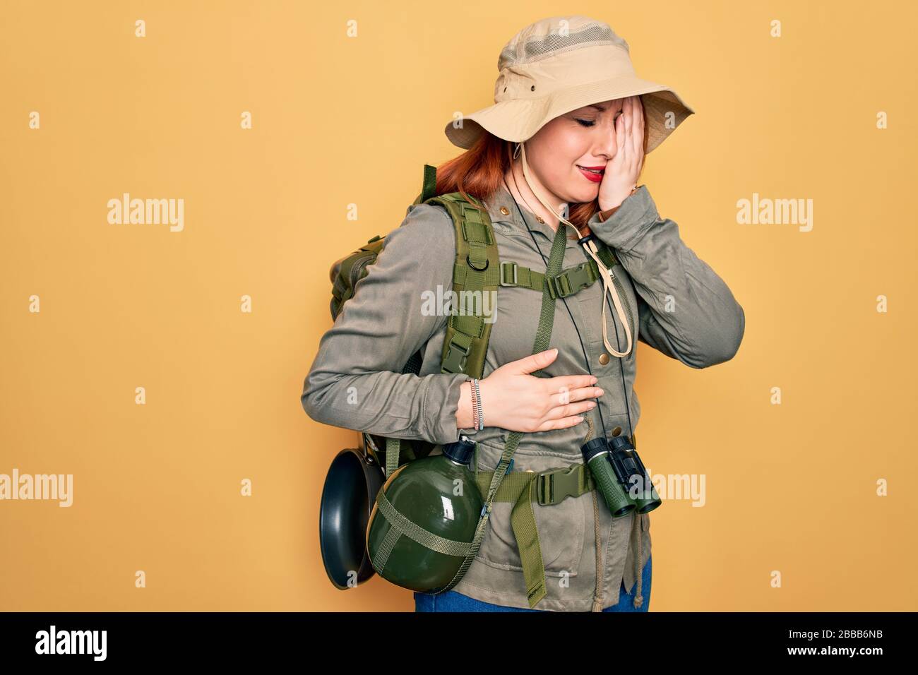 Young redhead backpacker woman hiking wearing backpack and hat over ...