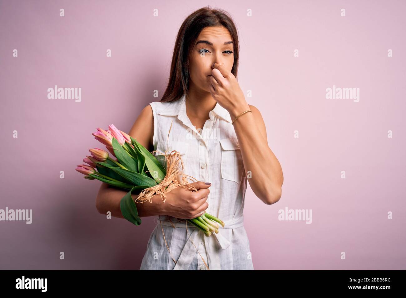 Young beautiful brunette woman holding bouquet of tulips flowers over ...