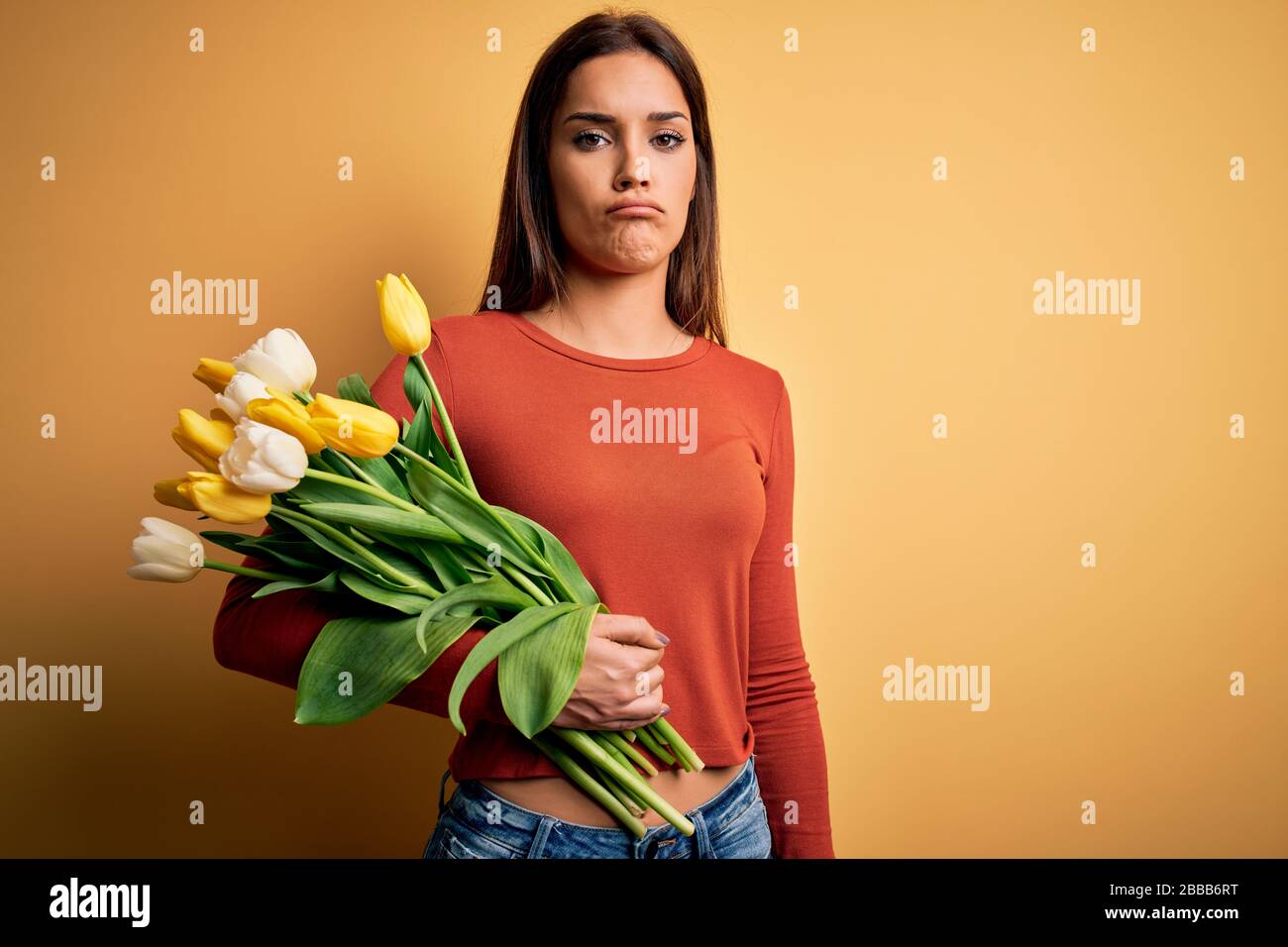 Young beautiful brunette woman holding bouquet of tulips flowers over ...