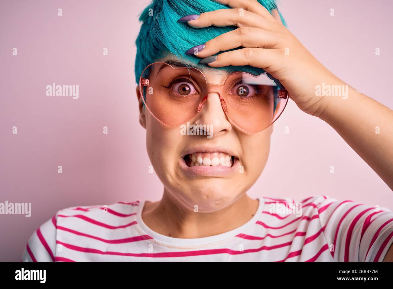 Young beautiful woman with blue fashion hair wearing fanny glasses with ...