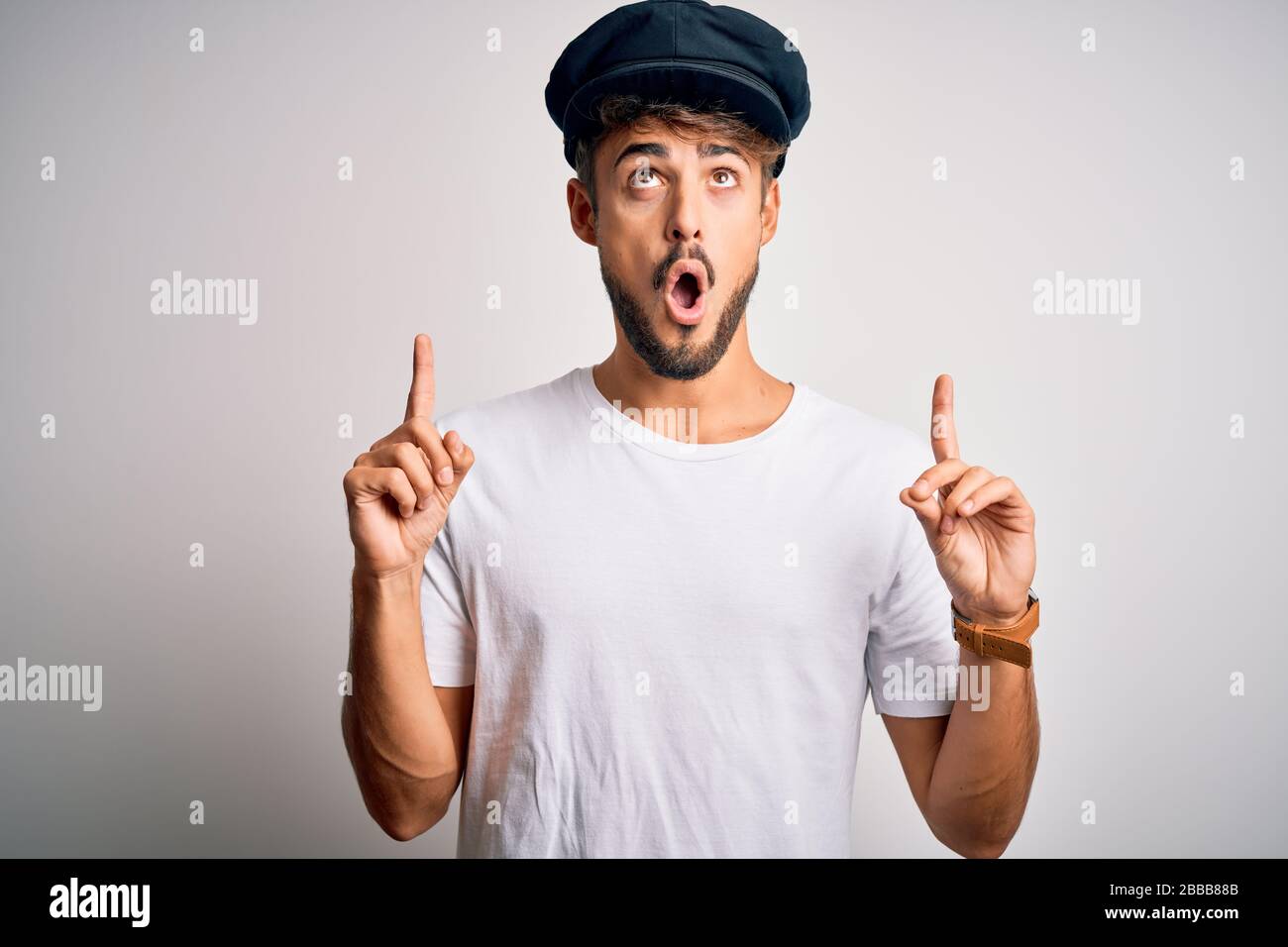 Young driver man with beard wearing hat standing over isolated white ...