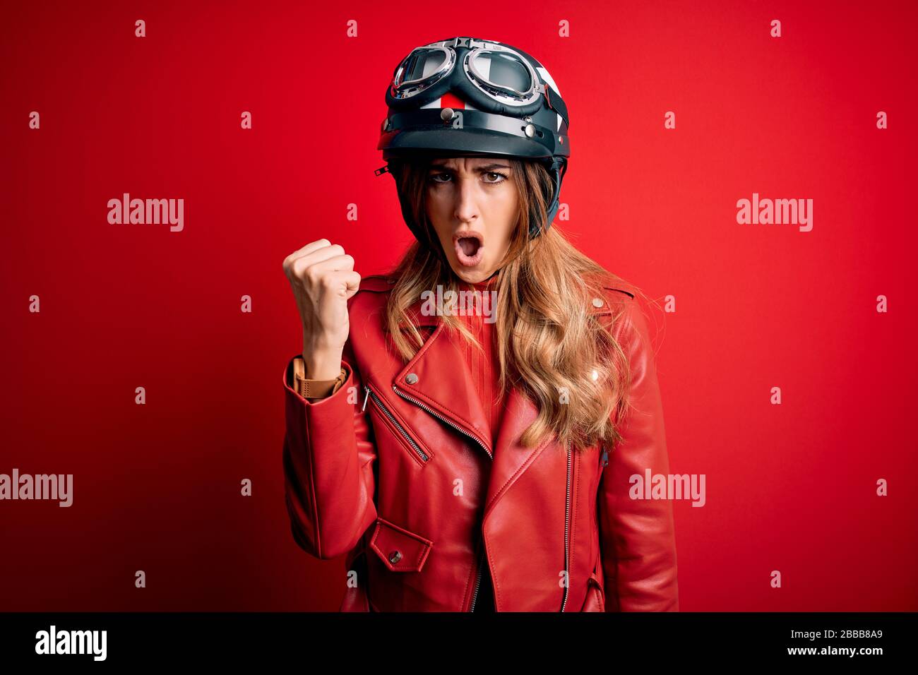 Young beautiful brunette motrocyclist woman wearing moto helmet over ...