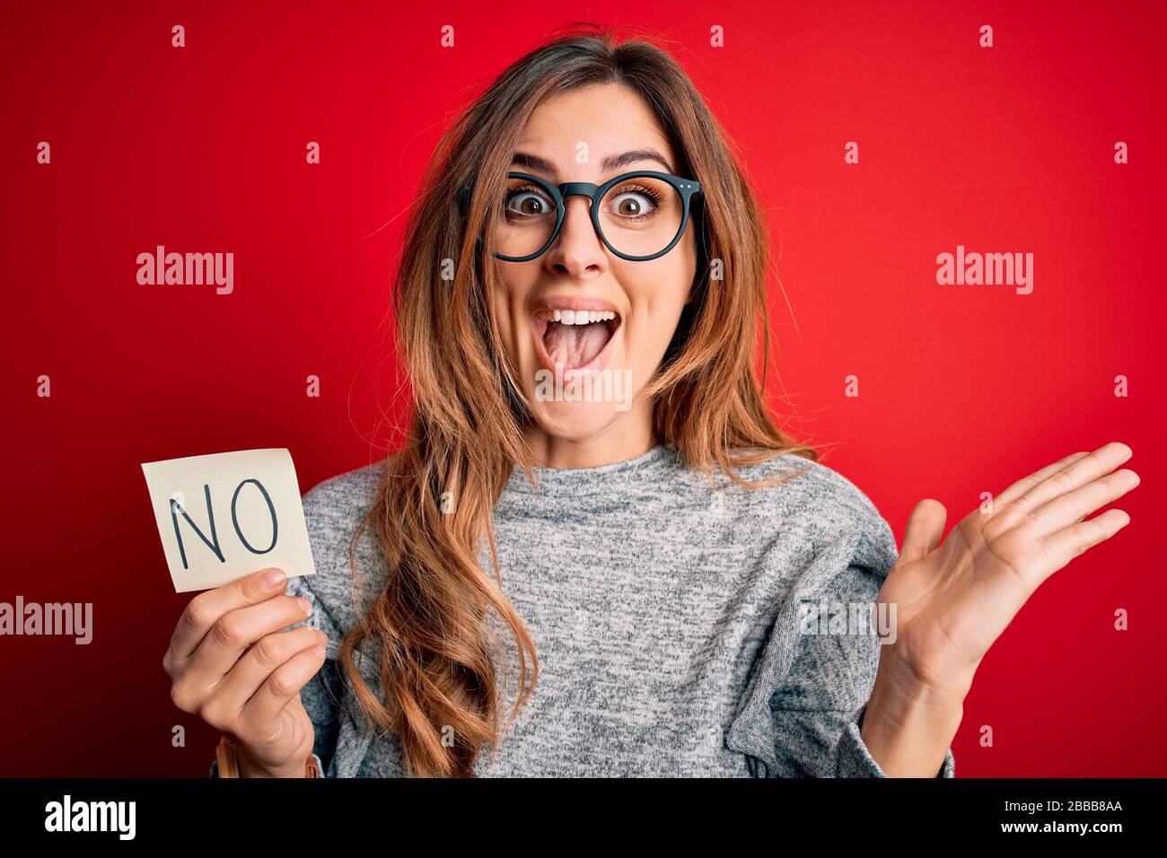 Young beautiful brunette woman holding reminder paper with no message ...