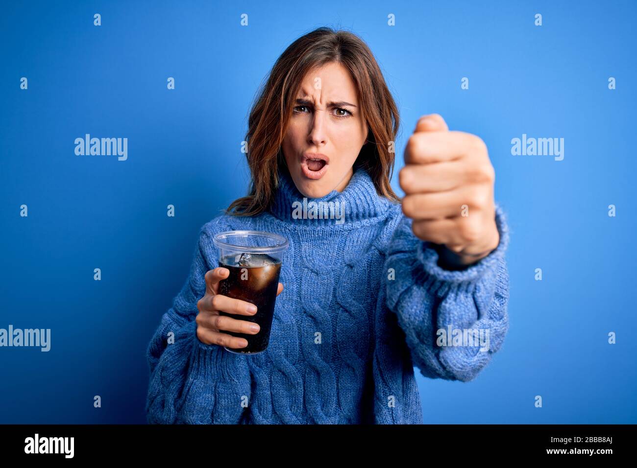 Young beautiful brunette woman drinking glass with cola refreshment ...