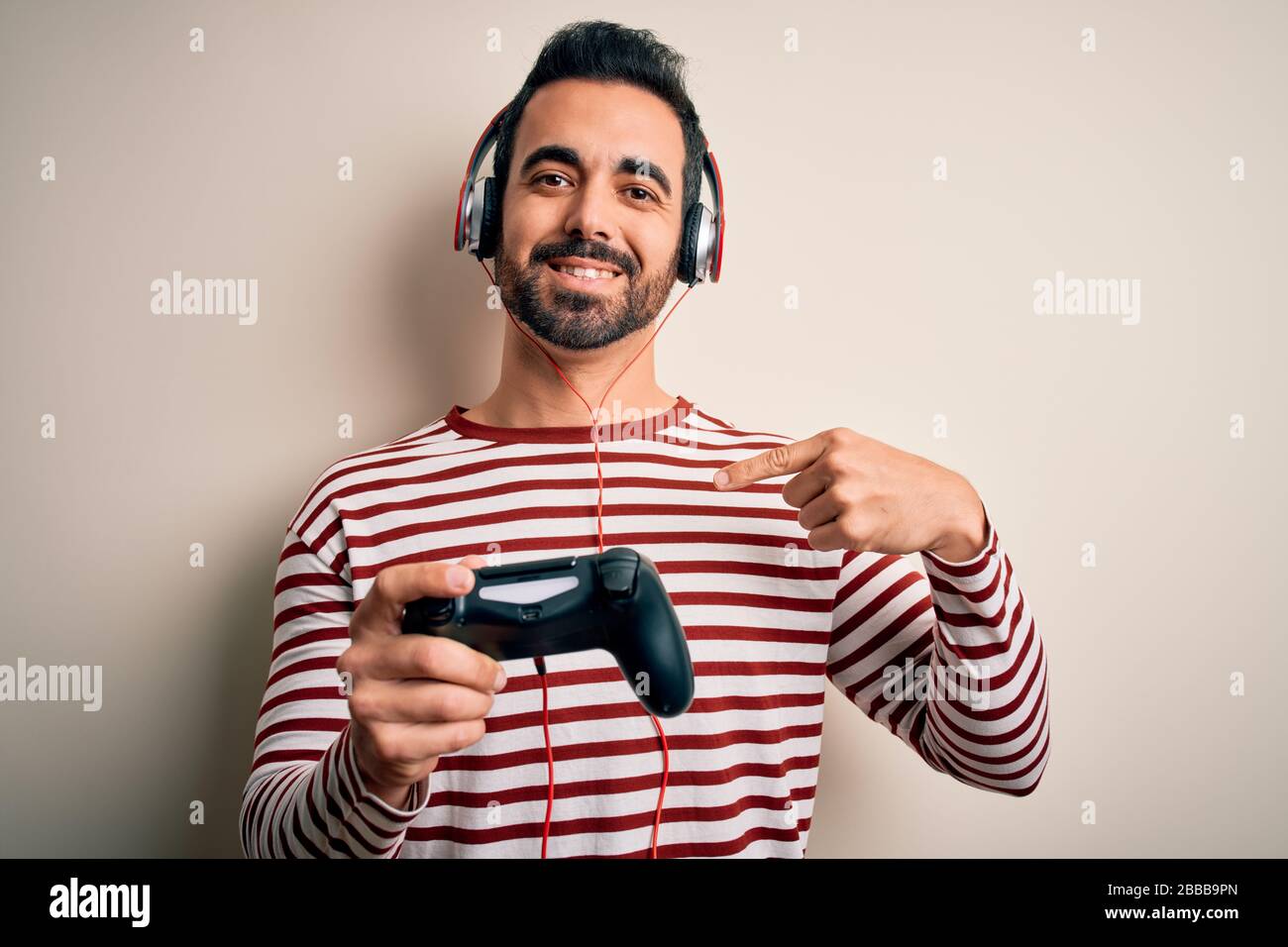 Young handsome gamer man with beard playing video game using joystick ...