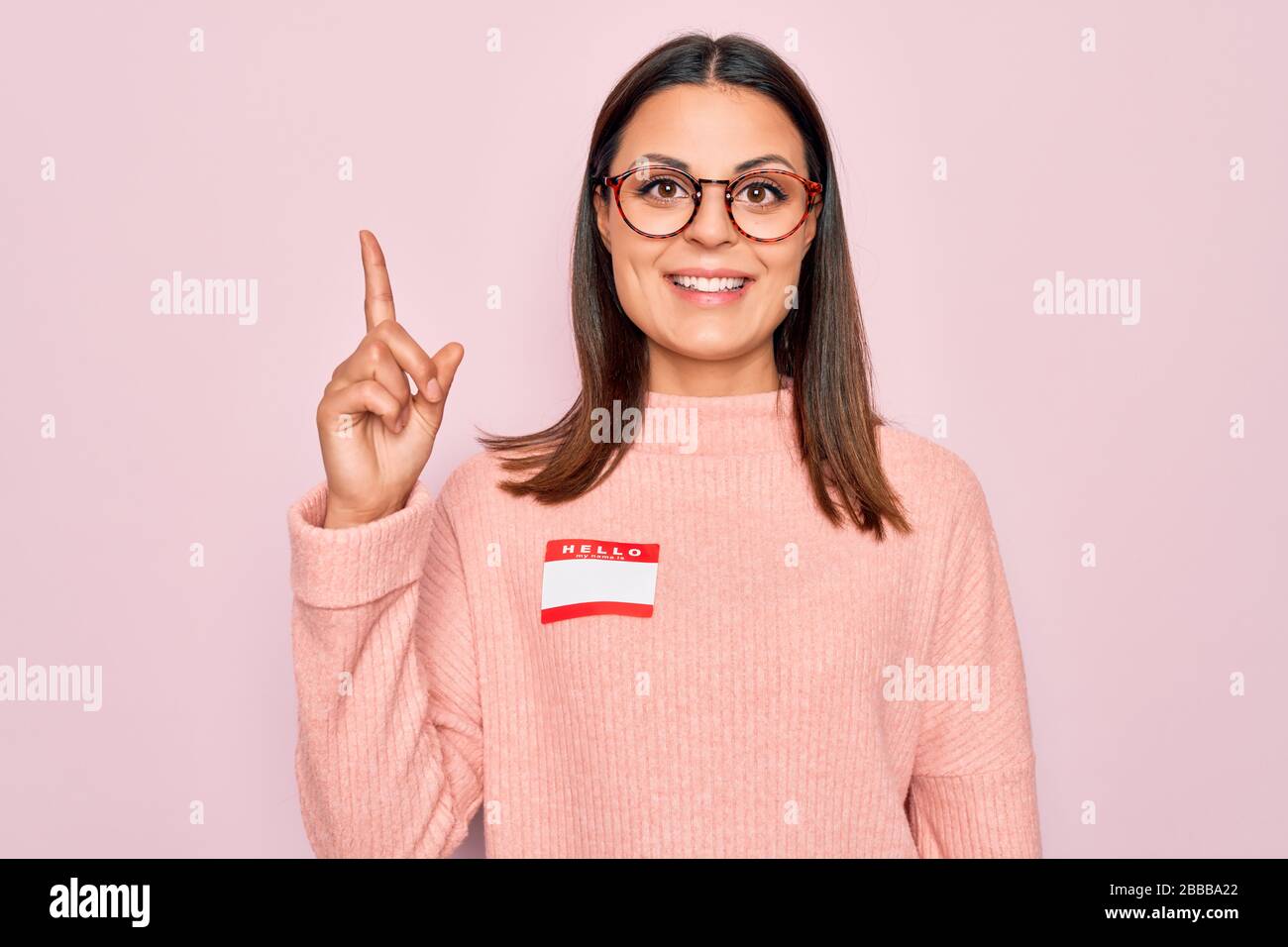 Young beautiful brunette woman wearing sticker with hello my name is ...