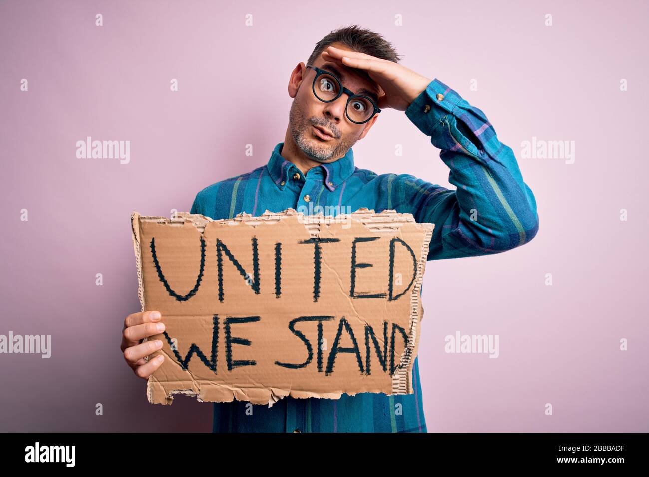 Young handsome activist man asking for union holding banner with united ...