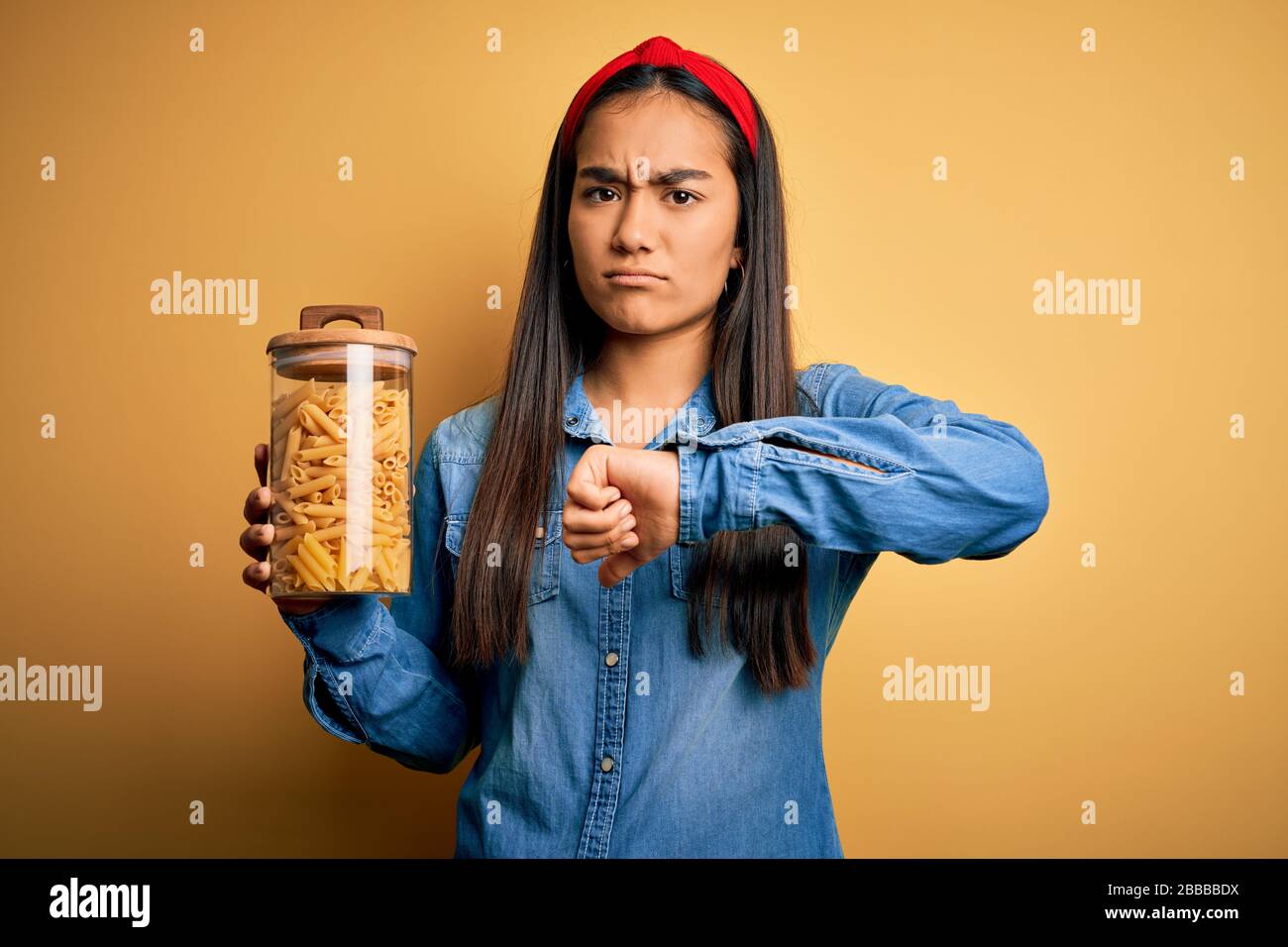 Young beautiful asian woman holding jar of Italian dry pasta macaroni ...