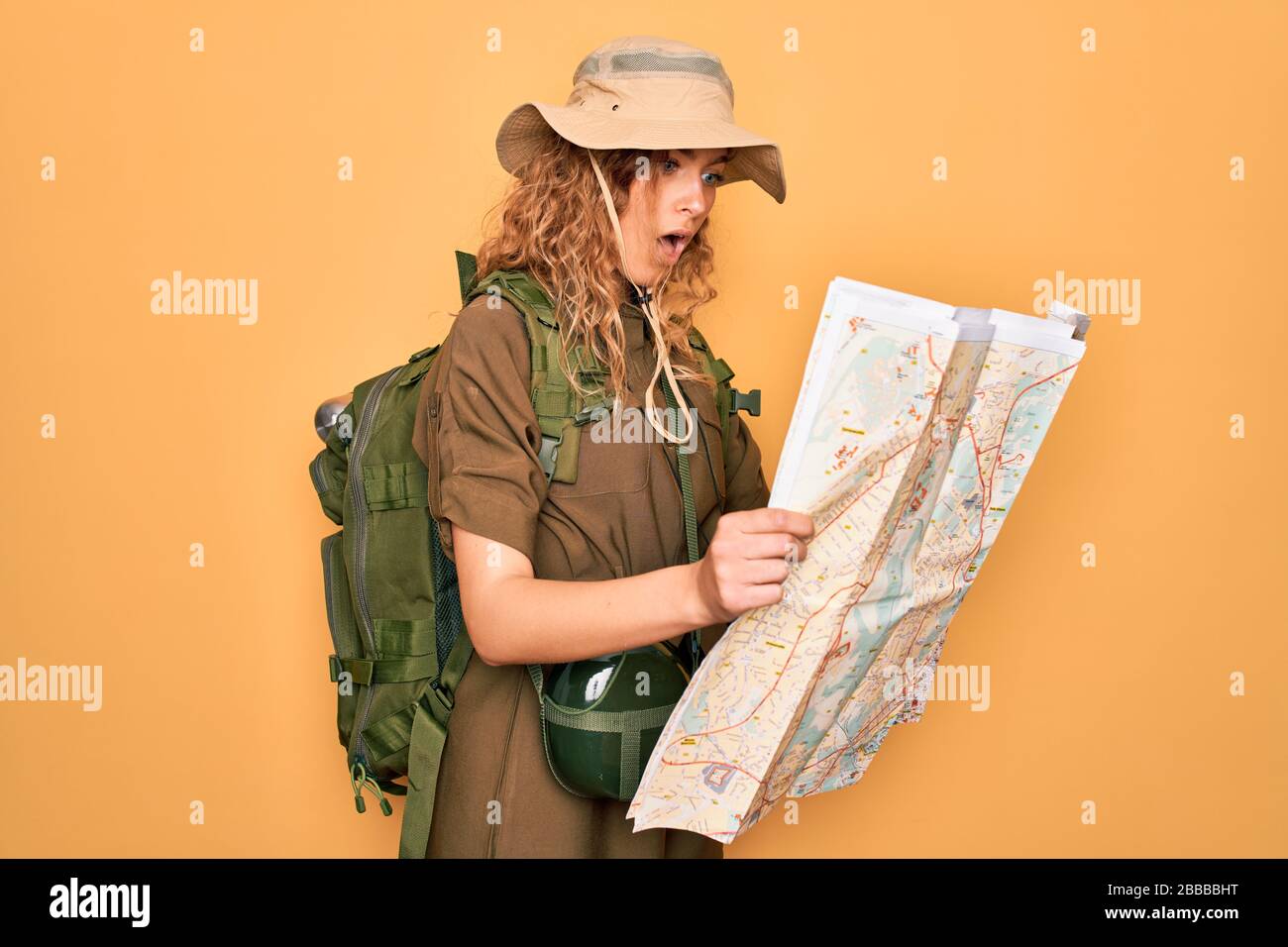 Young blonde explorer woman with blue eyes hiking wearing backpack ...