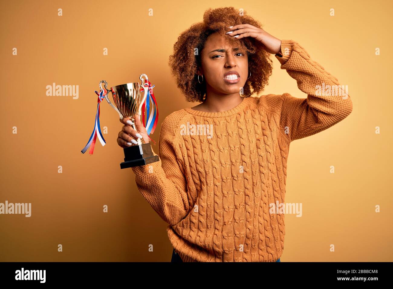 Young African American afro woman with curly hair holding winner ...