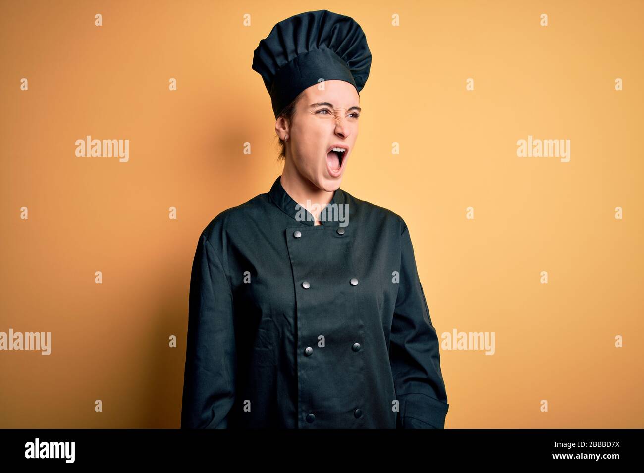 Young beautiful chef woman wearing cooker uniform and hat standing over ...