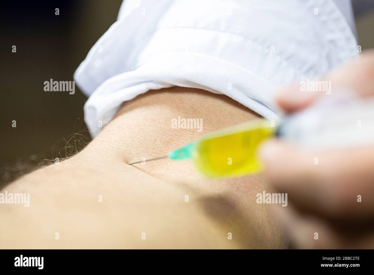 Syringe with yellow liquid inside. While being injected into the human ...