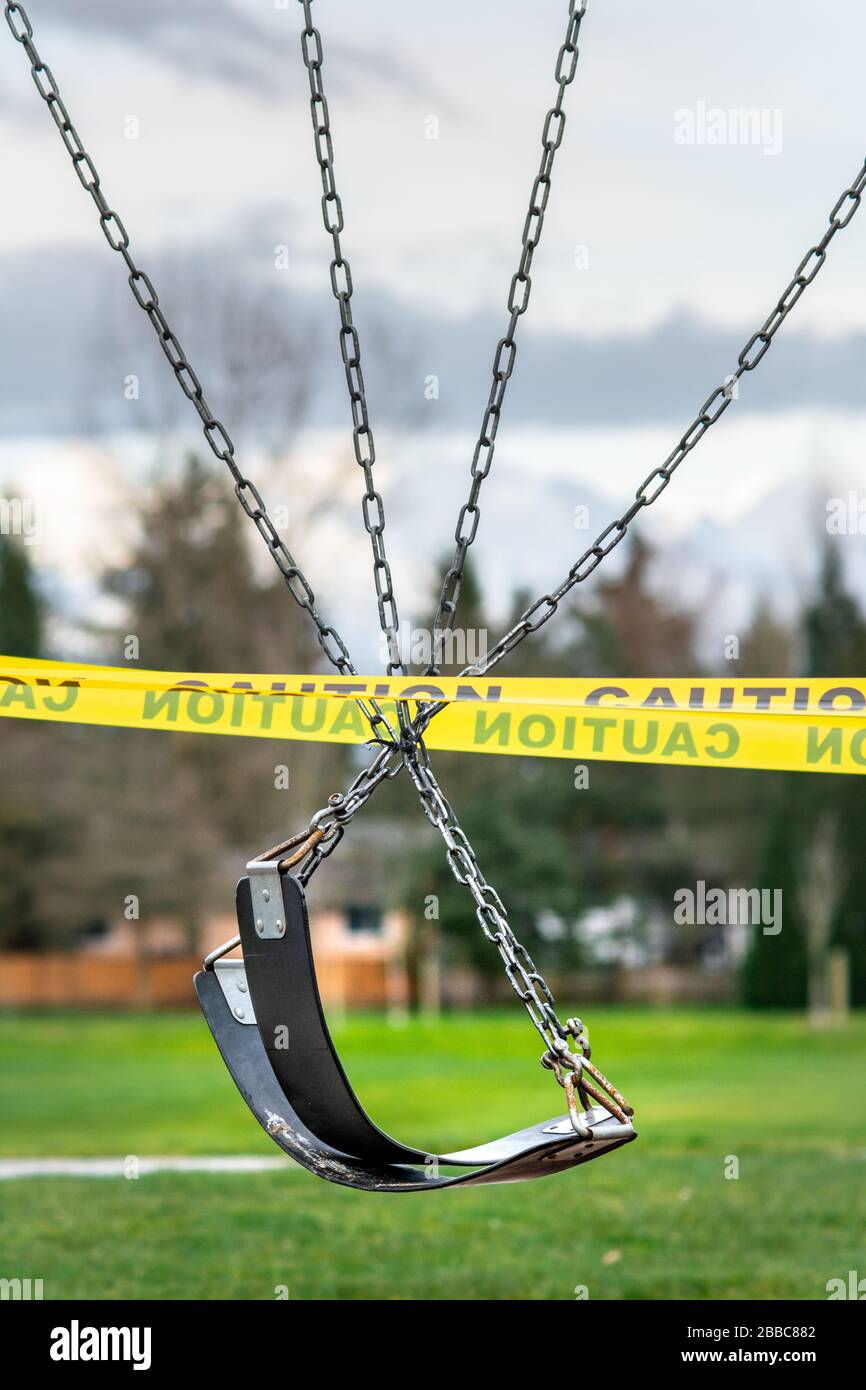 Black rubber swings on chains in closed public playground surrounded by ...