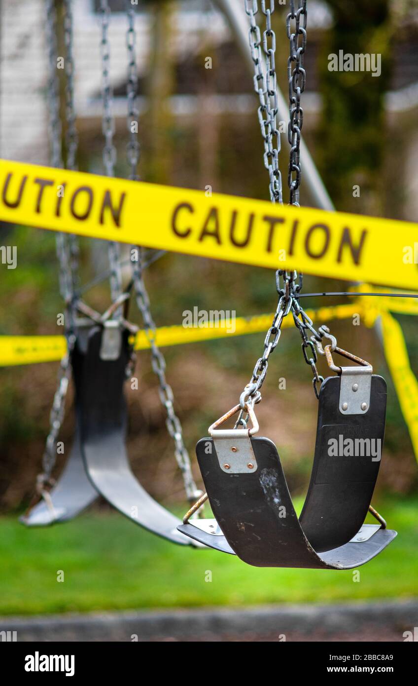 Black rubber swings on chains in closed public playground surrounded by ...