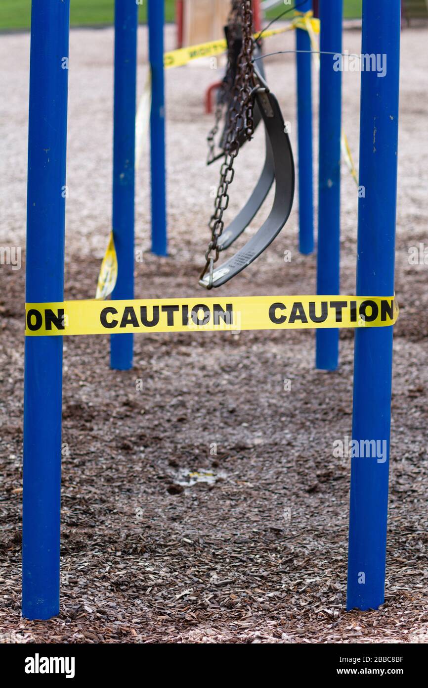 Black rubber swings on chains in closed public playground surrounded by ...