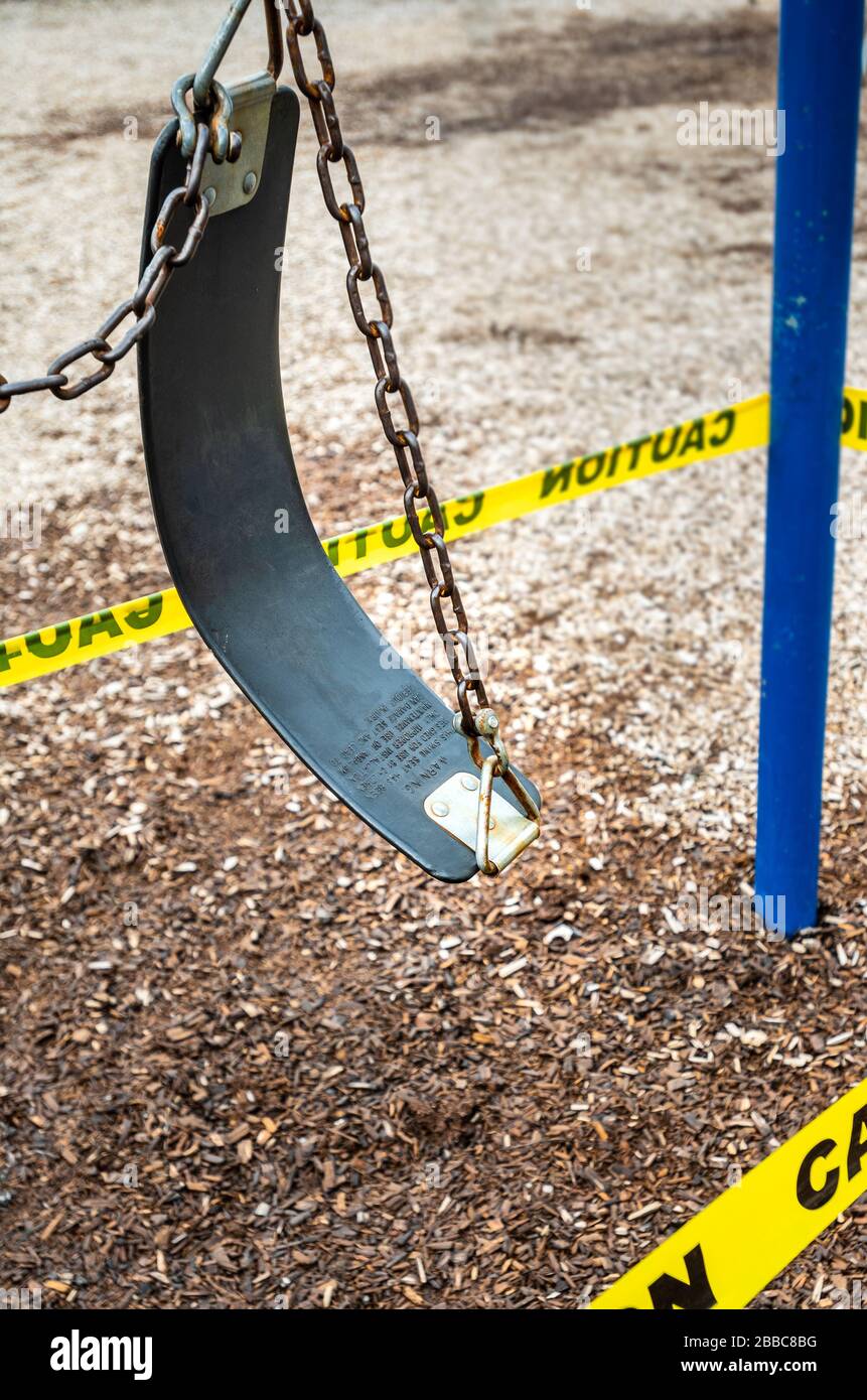 Black rubber swiing on chains in closed public playground surrounded by ...