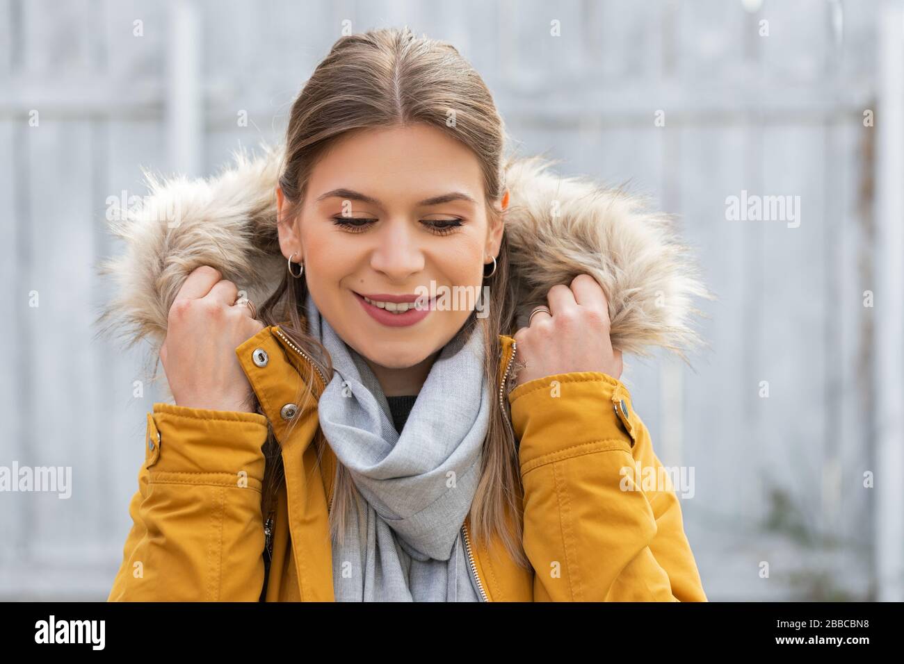 Portrait of an attractive young woman wearing yellow parka jacket ...