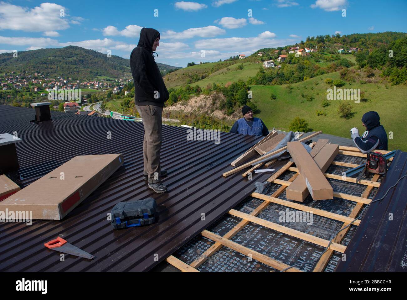 Construction workers working on new roof structure of building on ...
