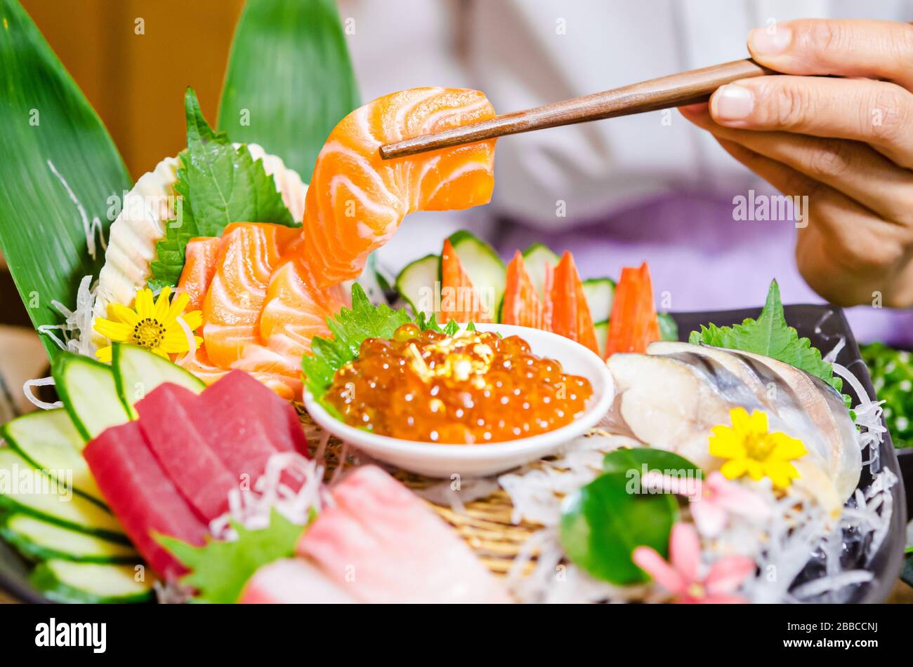 Salmon sashimi in chopsticks on sashimi set table in Japanese ...