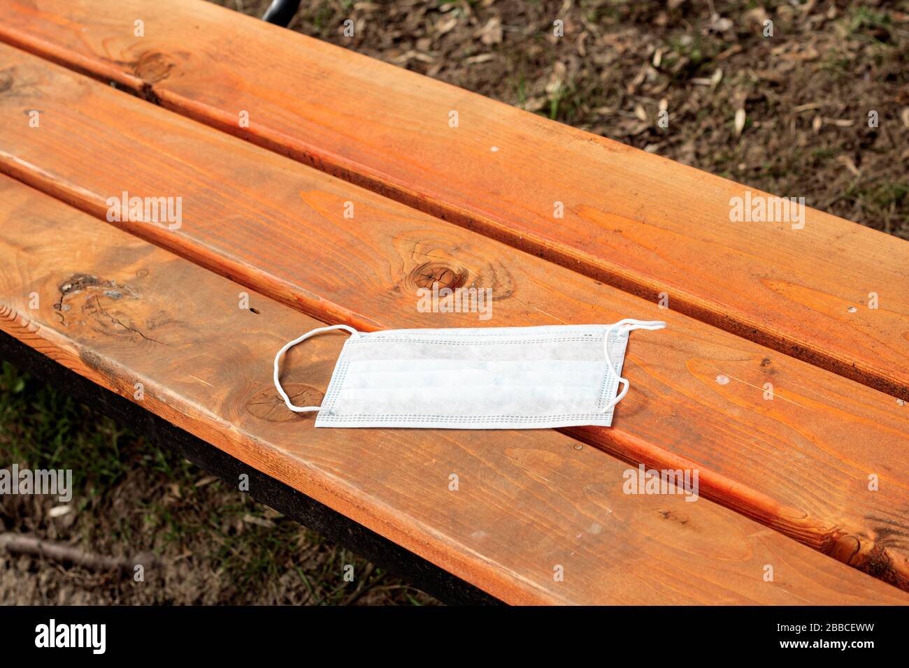 Protective medical mask forgotten on park bench Stock Photo - Alamy