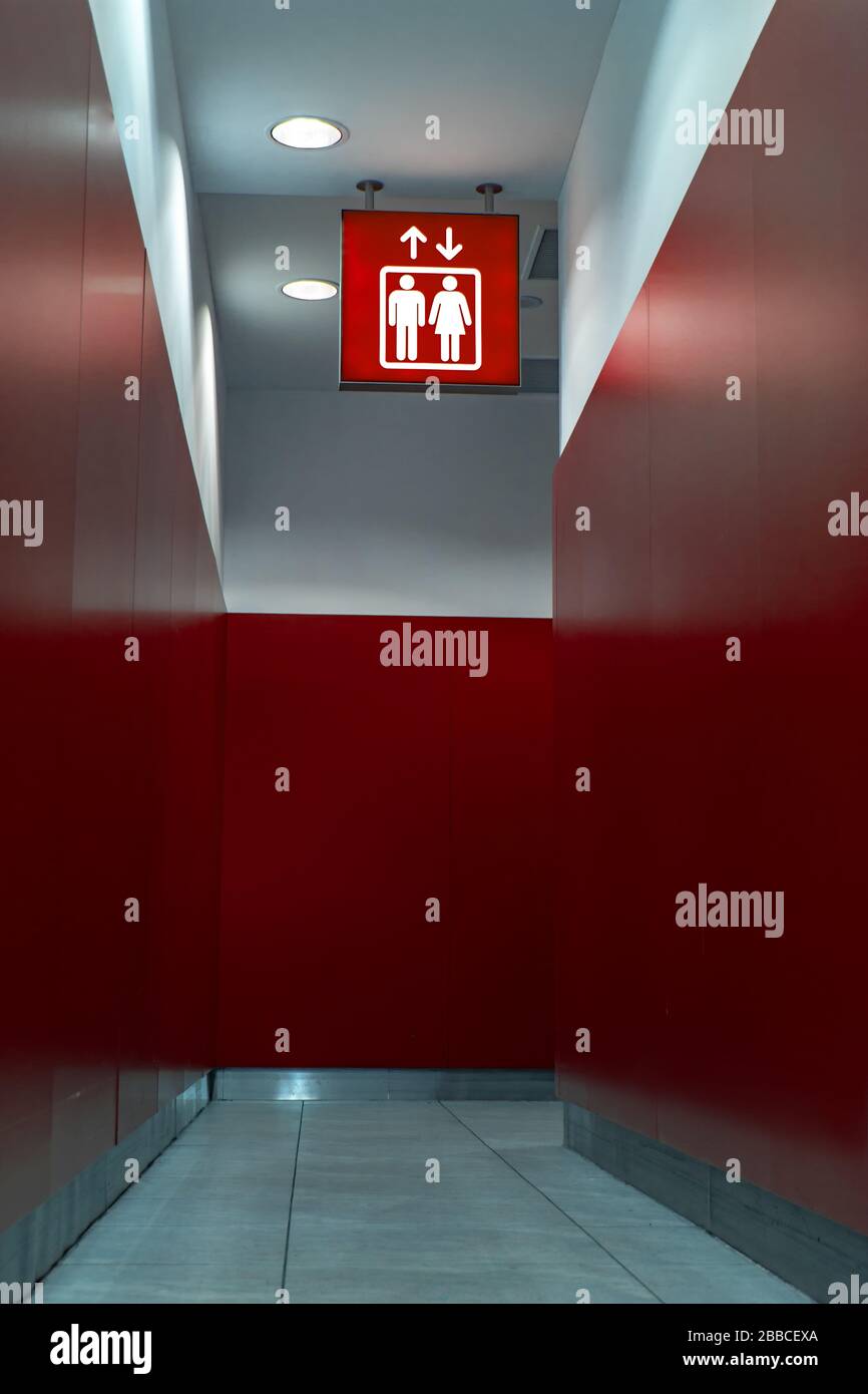 An illuminated sign with the icon of a lift hang on ceiling of the red ...