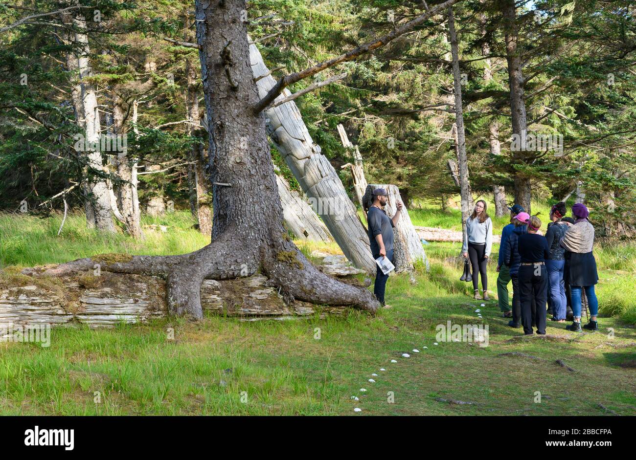 Visitors explore around Old Haida Poles at Skedans, also known as Koona ...
