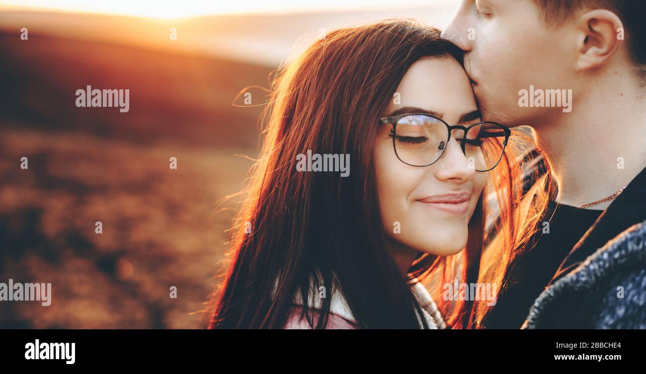 Charming caucasian couple kissing and embracing closely in a field with ...