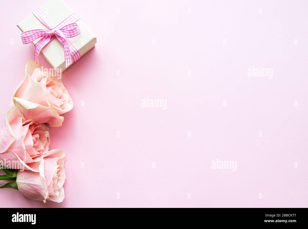 Gift box and pink roses on pink table top view. Flat lay. Birthday ...