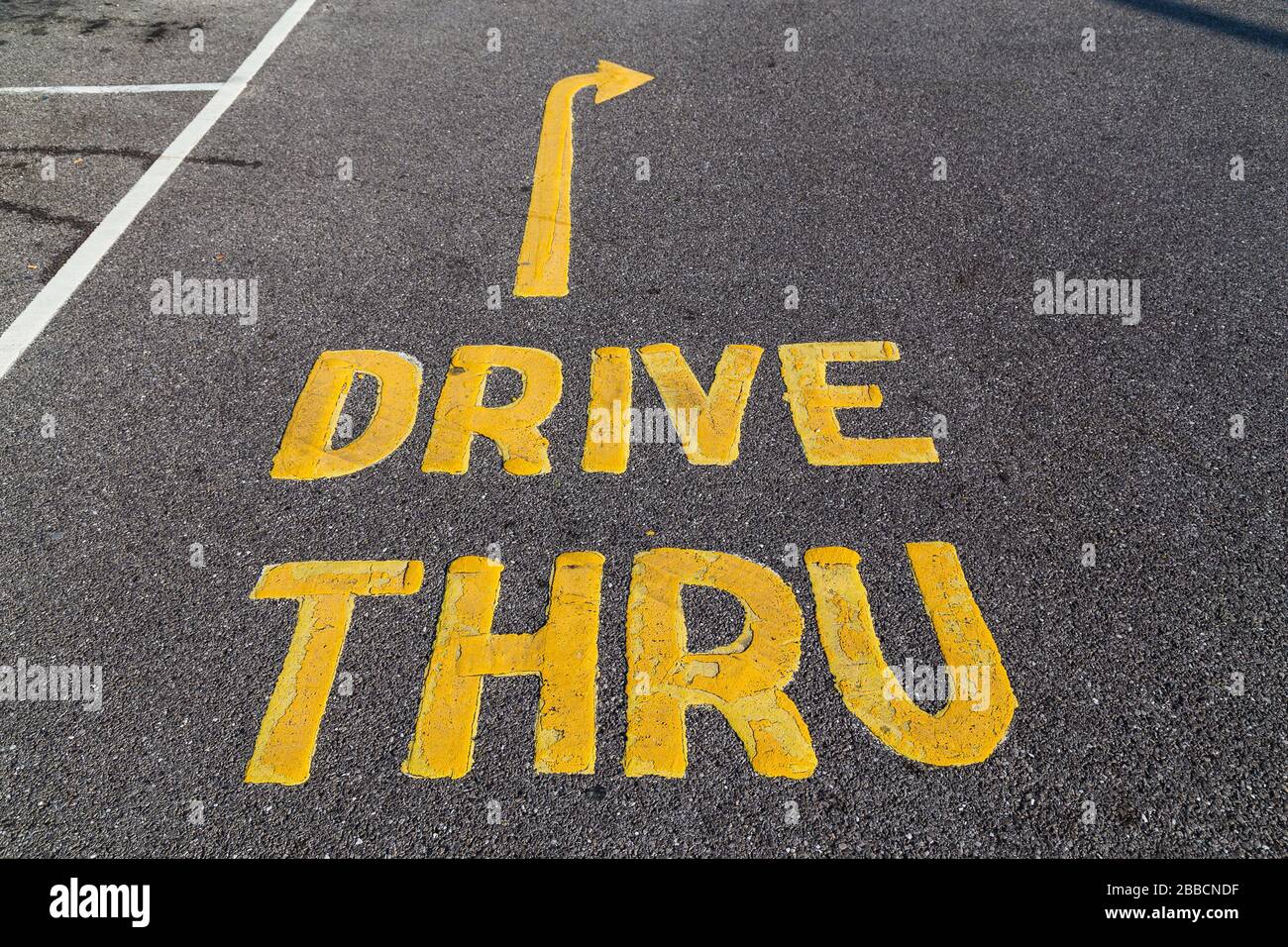 A sign for a drive through (drive thru) on a road. Written in yellow ...