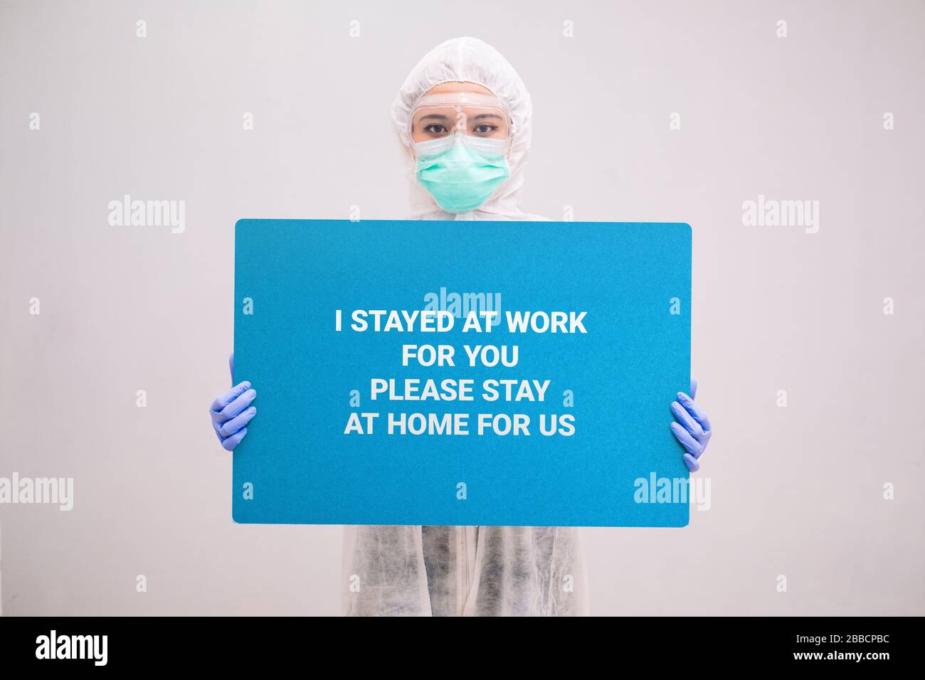 Nurse with disposable coverall and mask wearing safety glasses holding ...