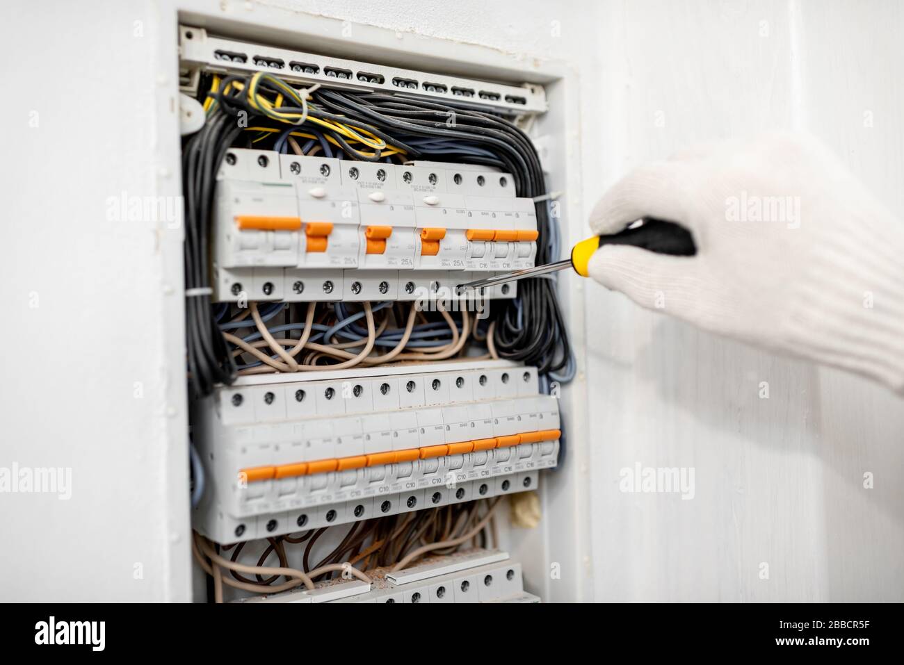 Electrician installing or repairing apartment electrical panel, close ...