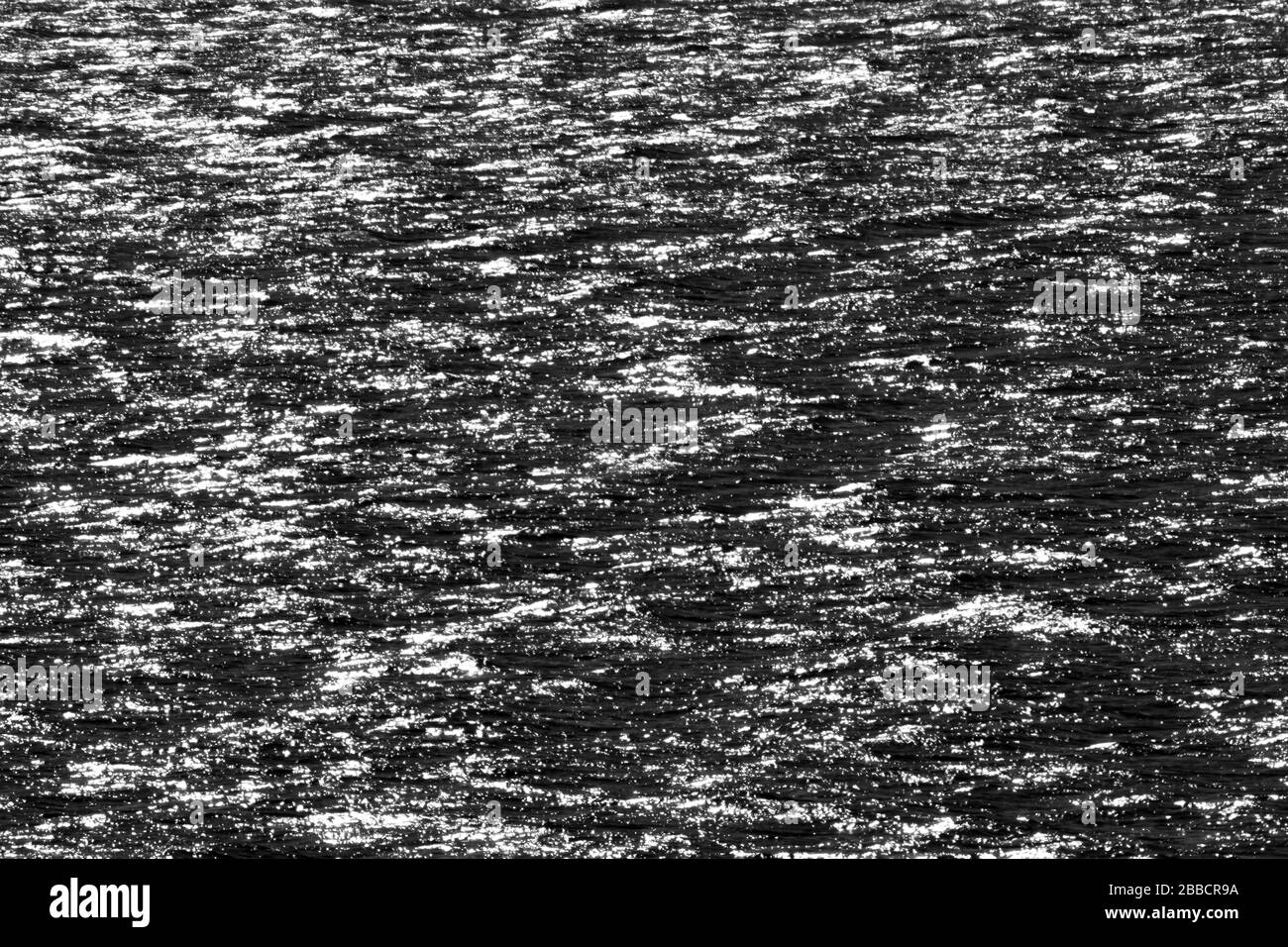 Pattern based on reflections of waves in silver and black in a dark sea ...