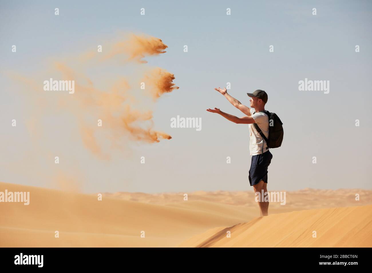 Happy traveler in desert. Young man throwing sand in wind. Abu Dhabi ...