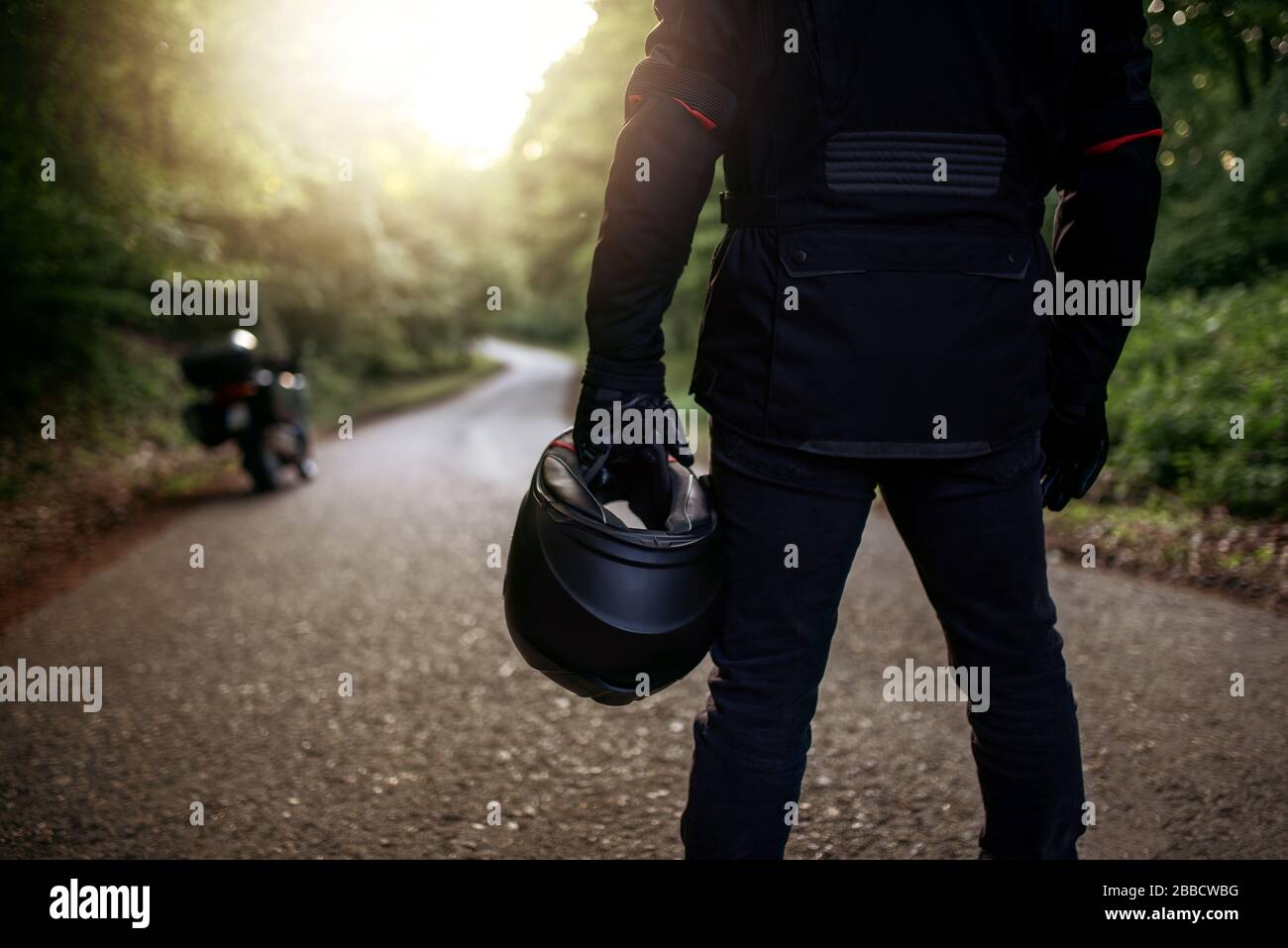 Motorcycle guy in raiders clothes, gearing up. A young men stands near ...
