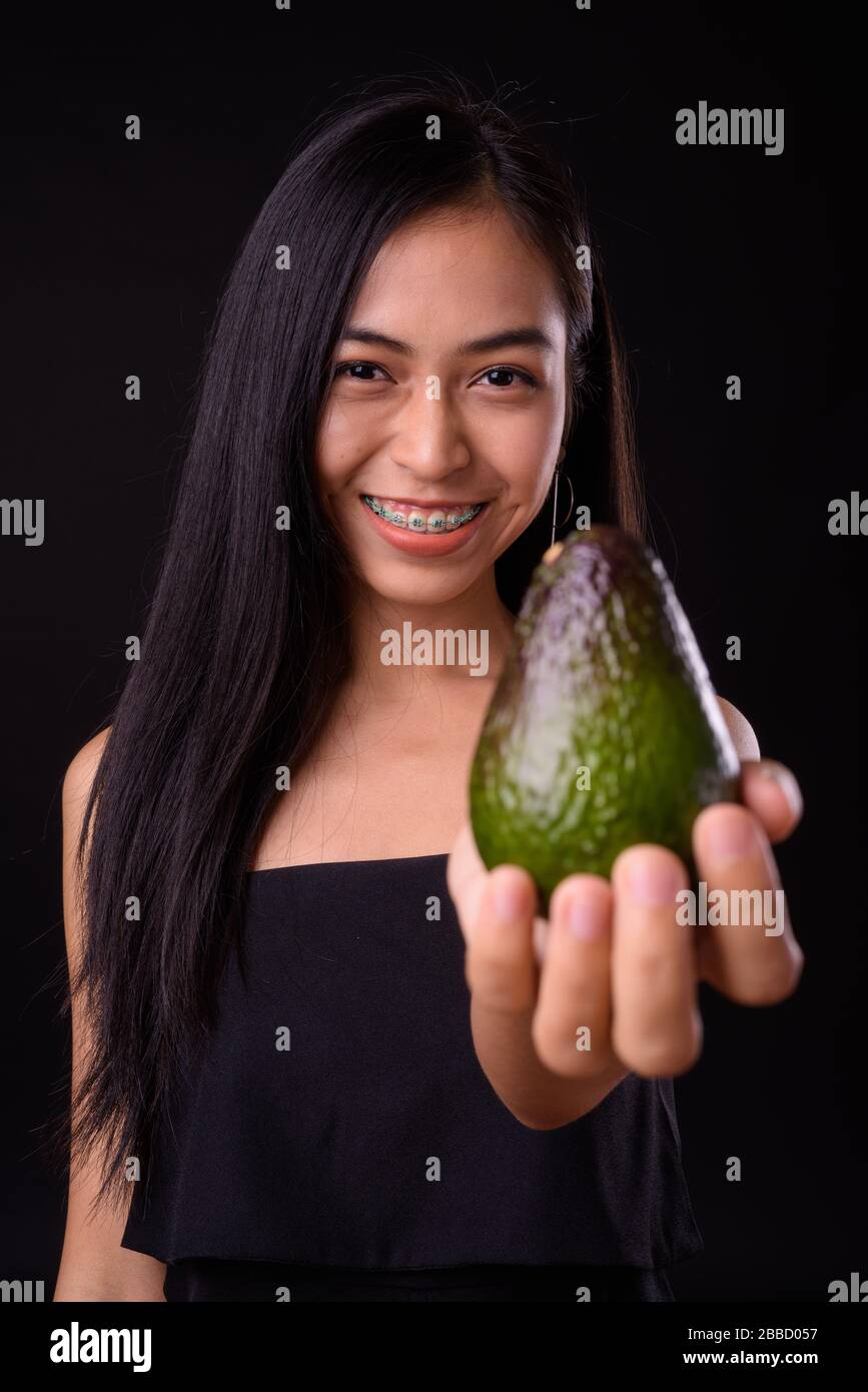 Portrait of happy young Asian woman giving avocado Stock Photo - Alamy