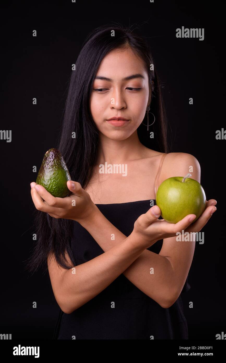 Portrait of young Asian woman thinking with apple and avocado Stock ...
