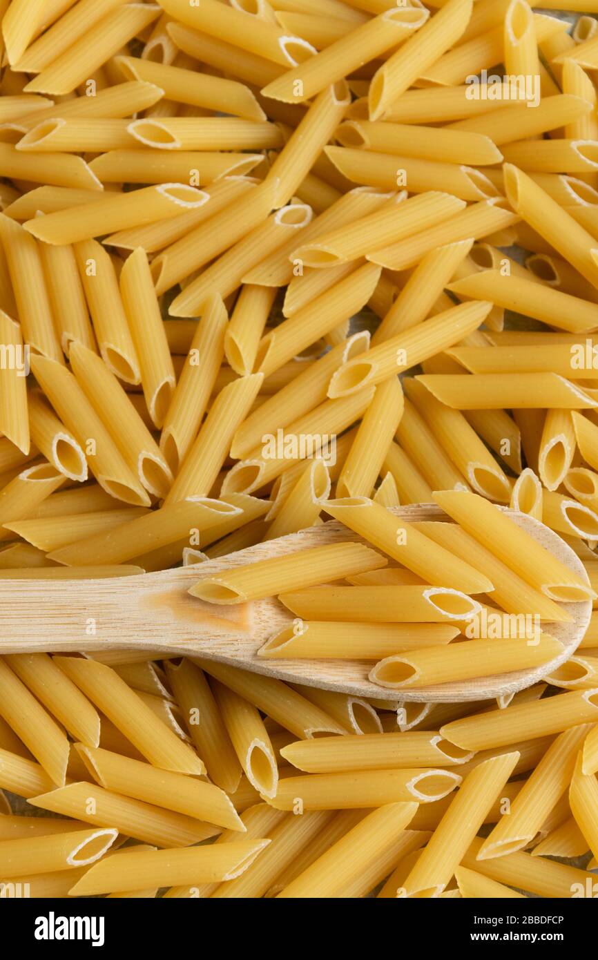 Food background - dry penne pasta and wooden spoon, whole wheat ...
