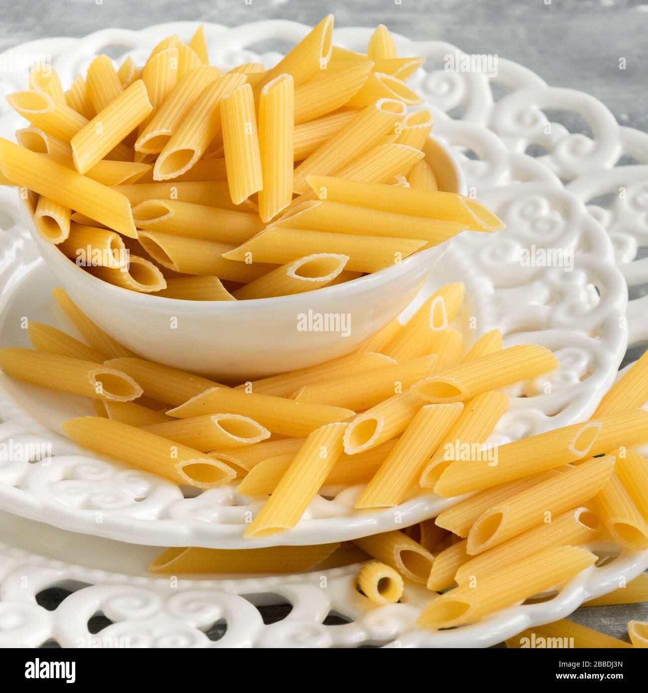 Dry penne pasta on blue white vintage plate, whole wheat uncooked ...