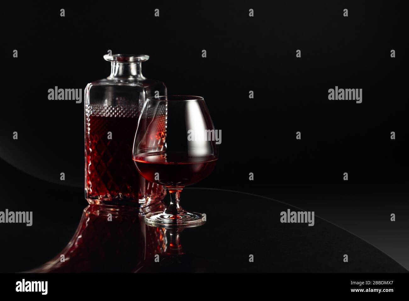 Glass of brandy and a carafe on a dark background. Fancy reflection on ...